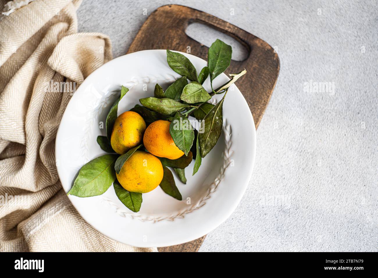 Fresh tangerines on a classic white plate over a textured beige napkin ...