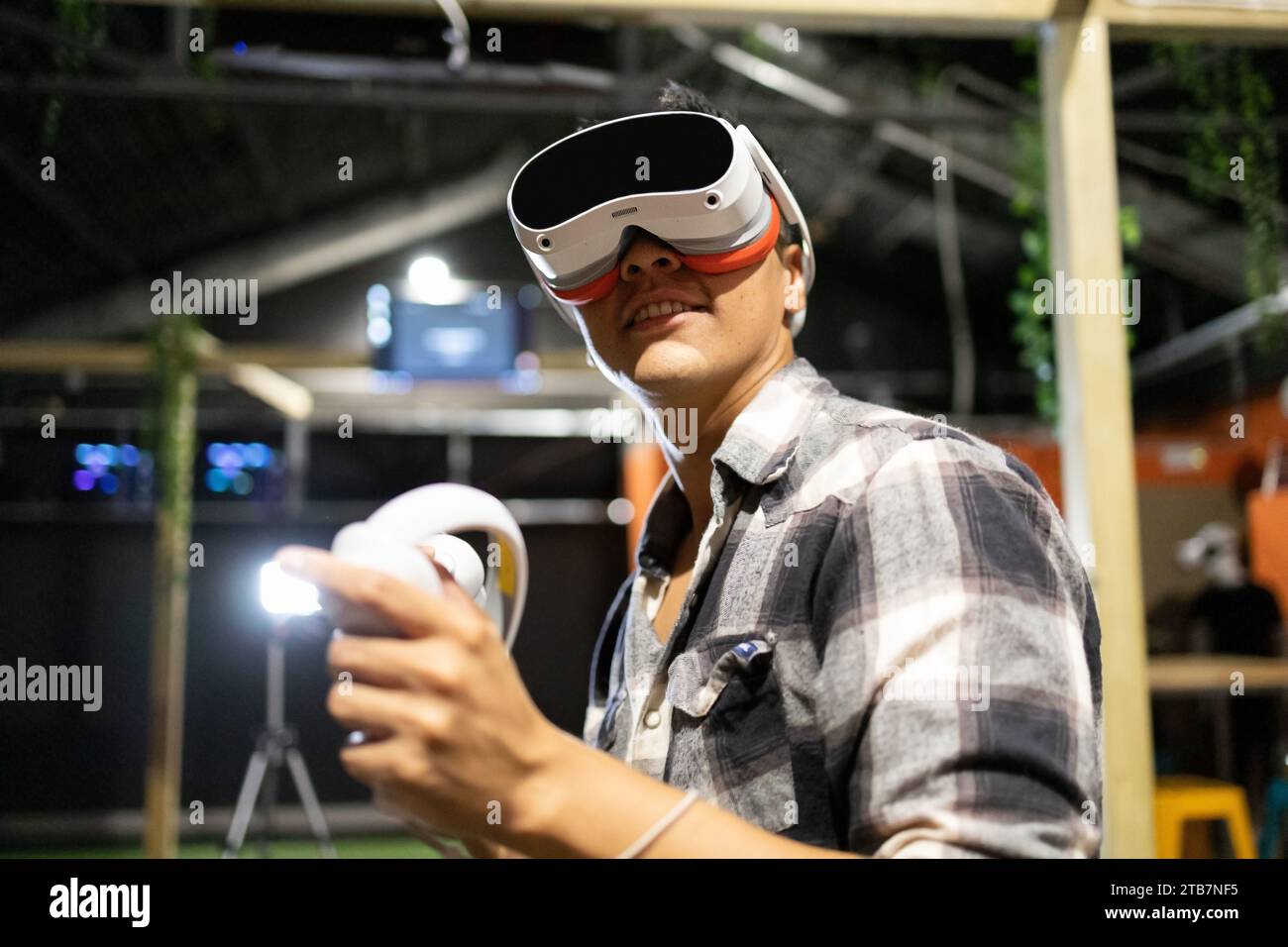 A young man is engaged with a virtual reality headset and controllers ...