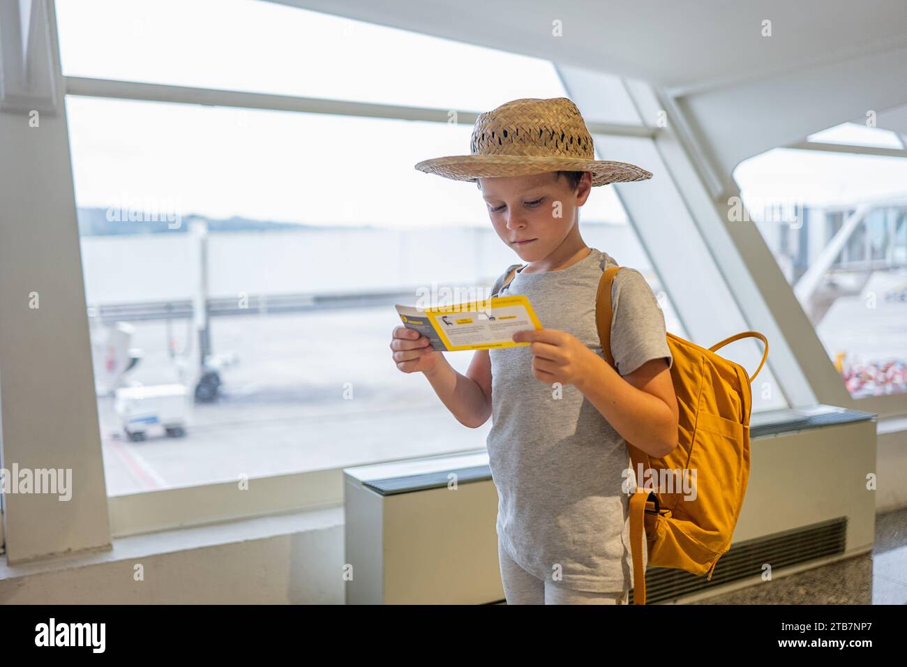 Portrait of cute thoughtful boy in casuals and straw hat standing at ...