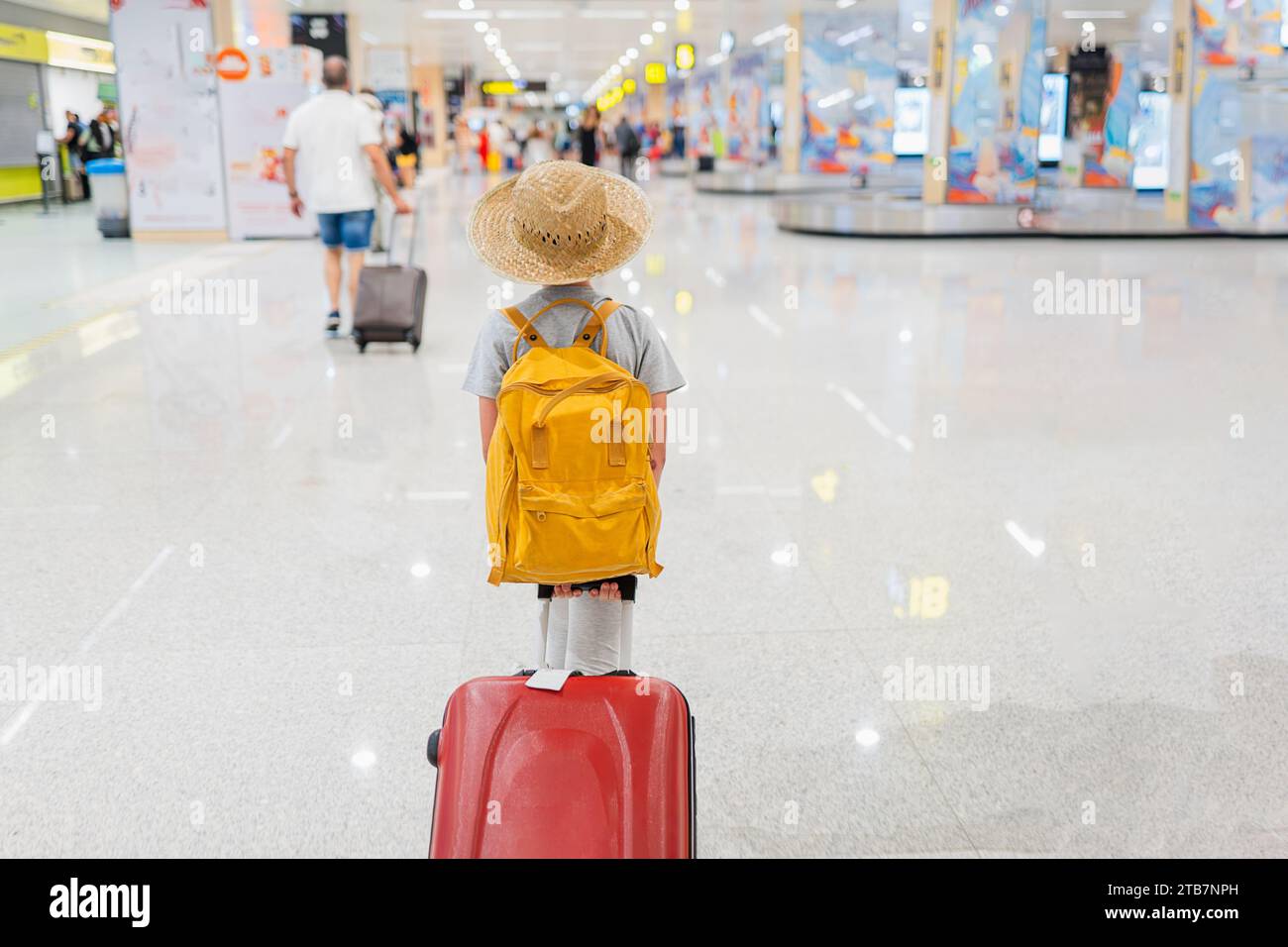 Back view of anonymous kid wearing hat and backpack pulling red ...