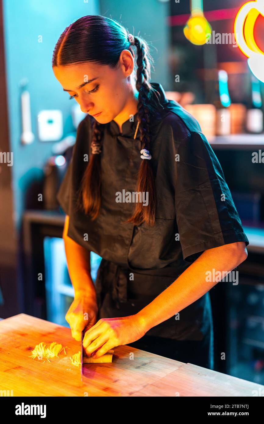 Focused young female chef with braids in black uniform with focus ...