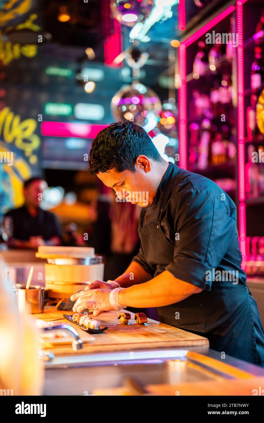 Side view of Confident young male chef with in black uniform and gloves ...