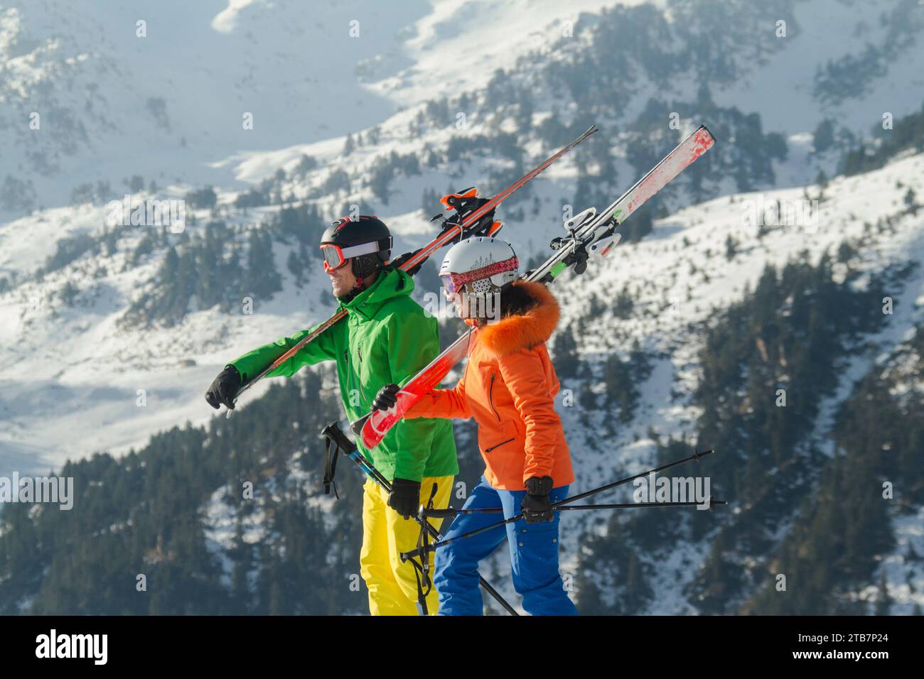 Couple carrying skis on their shoulders enjoying the Swiss Alps Stock ...