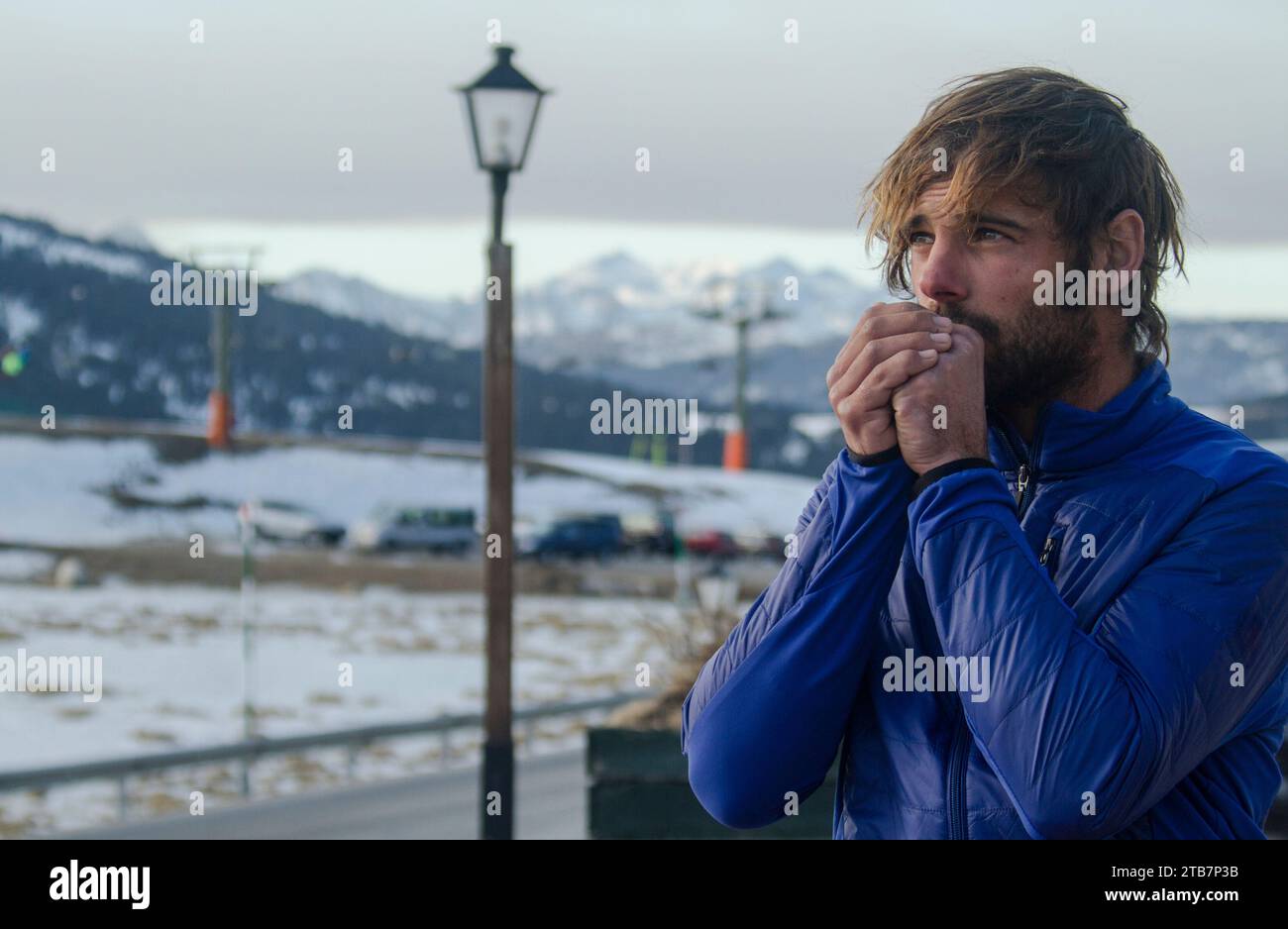 Man warms hands with breath in cold Swiss Alps backdrop Stock Photo - Alamy