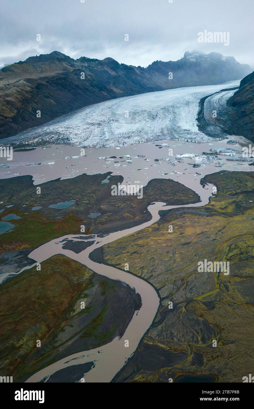 An aerial shot captures the sprawling beauty of a glacier flowing into ...