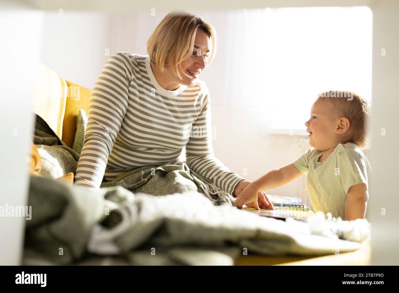 A heartwarming scene with a smiling mother engaging with her curious ...