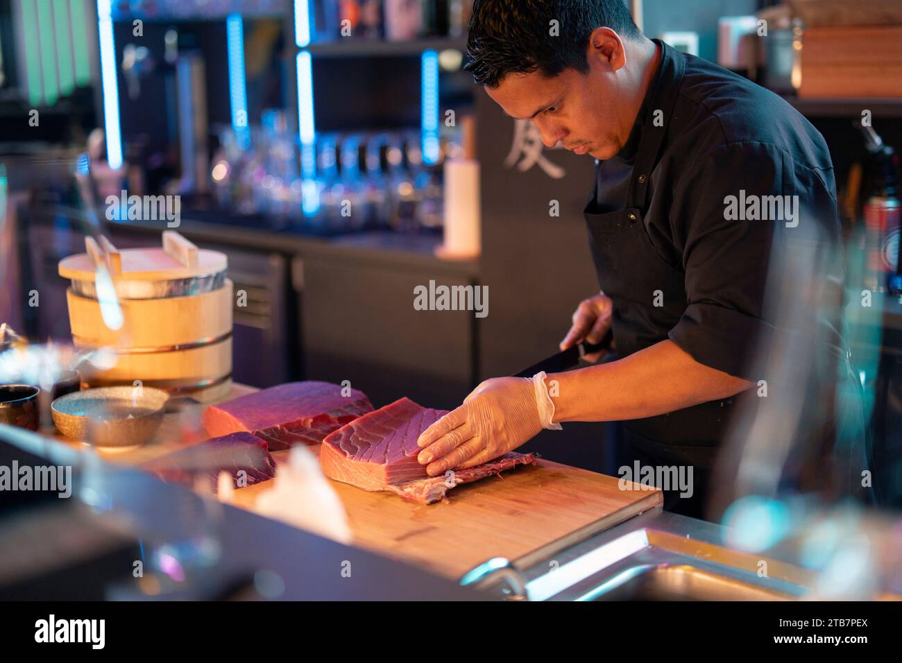 A sushi chef attentively slices fresh fish with a sharp knife at a ...