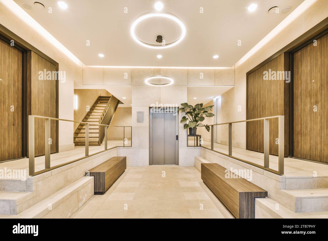 Illuminated lobby with stairs and wooden benches and modern elevator in ...
