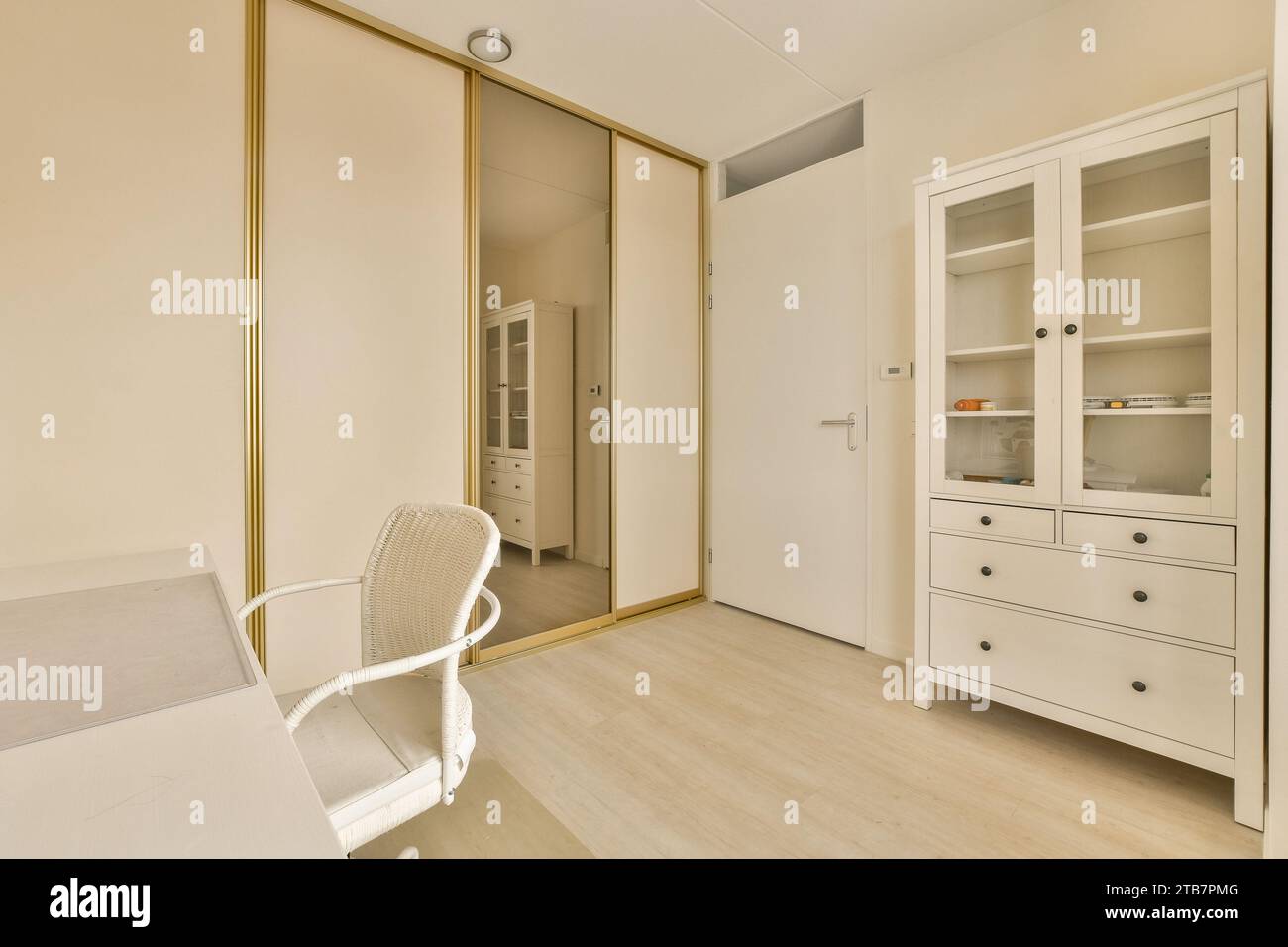 White wooden cupboard with chair and desk in spacious room with mirror ...