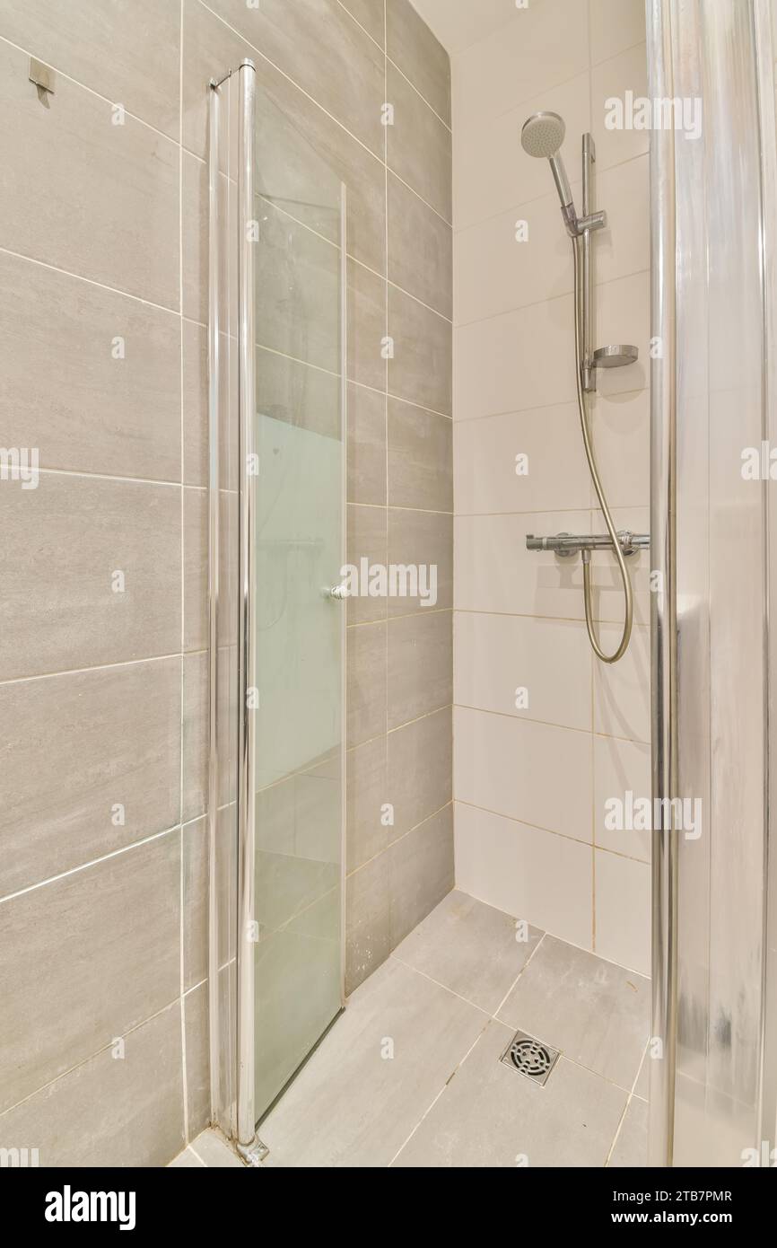 Shower booth with open glass door and tiled wall in illuminated ...