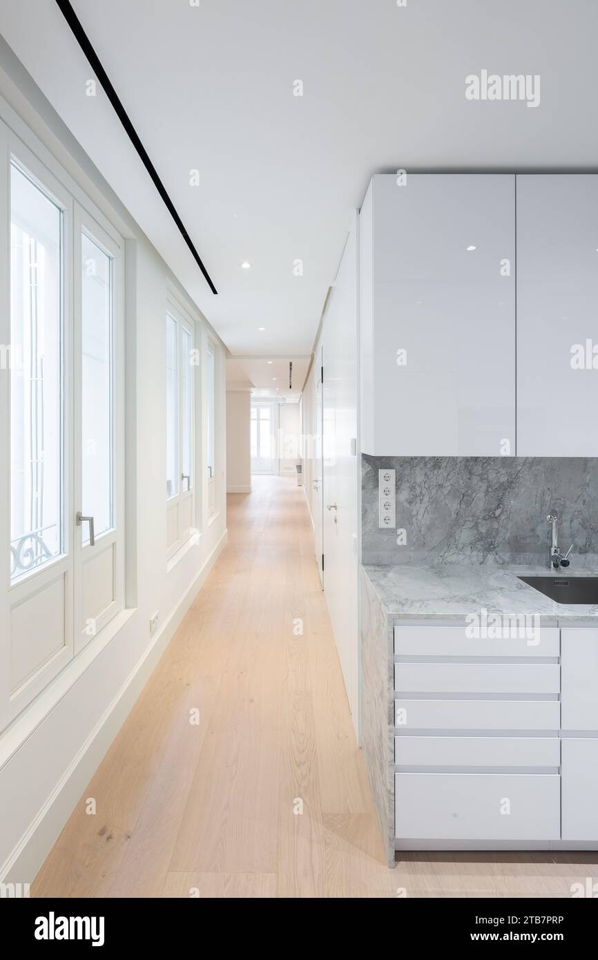 Narrow corridor with wooden floors, white cabinets, and marble ...