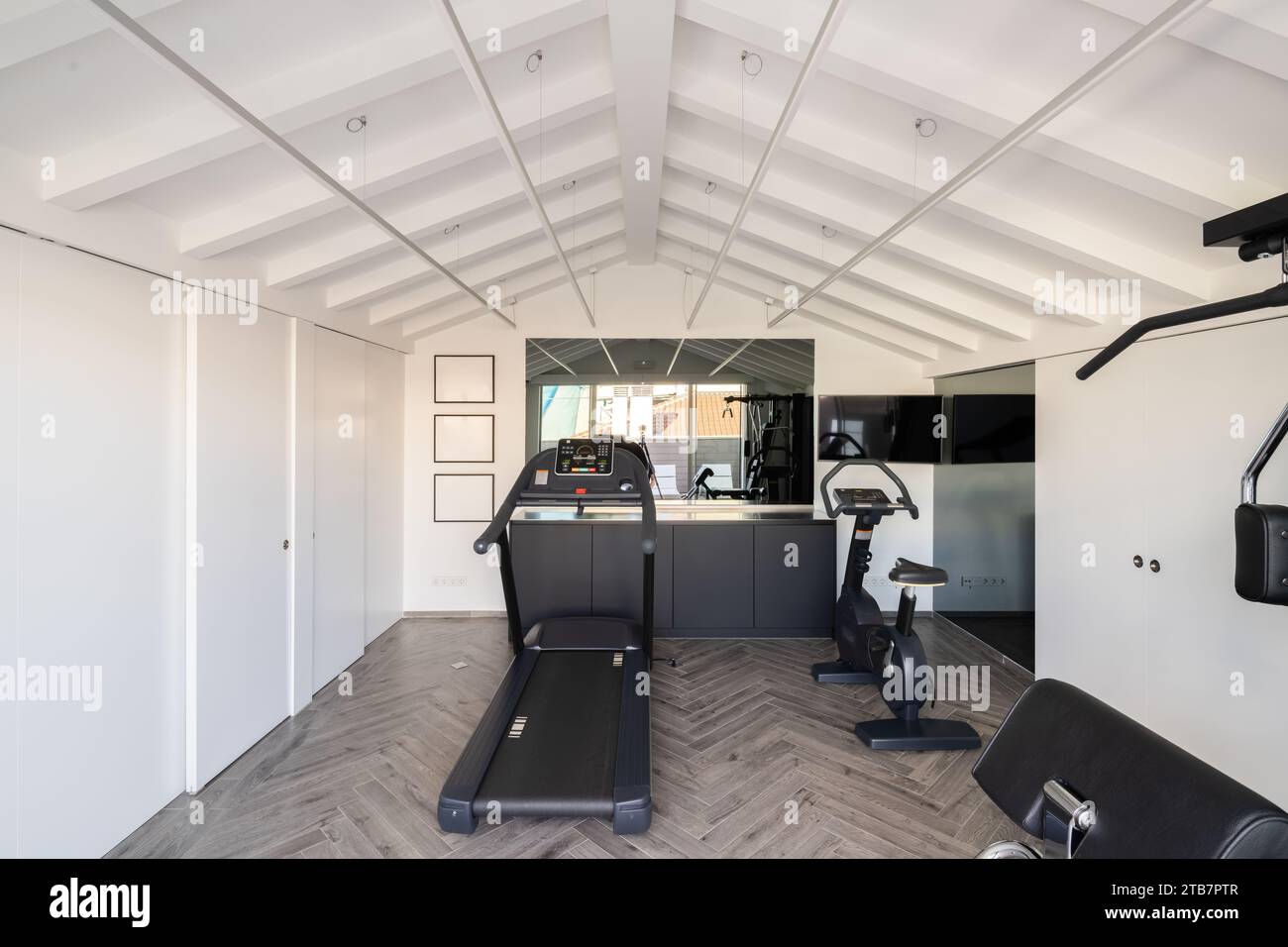 Treadmill and exercise bike in modern gym room with black cabinets and ...