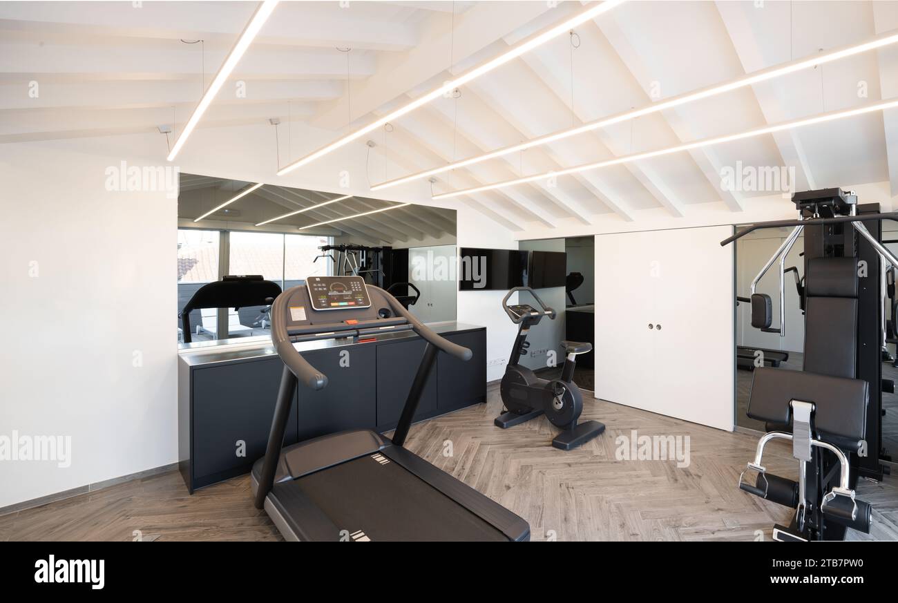 Treadmill and exercise bike in modern gym room with black cabinets and ...