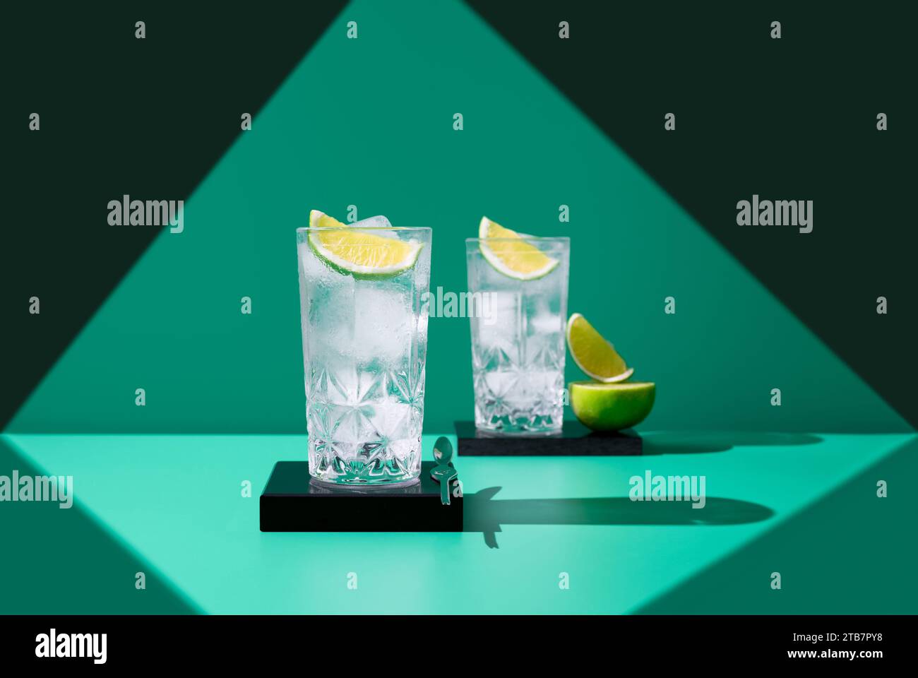 Two glasses of gin tonic with lime slices cast interesting shadows on a ...