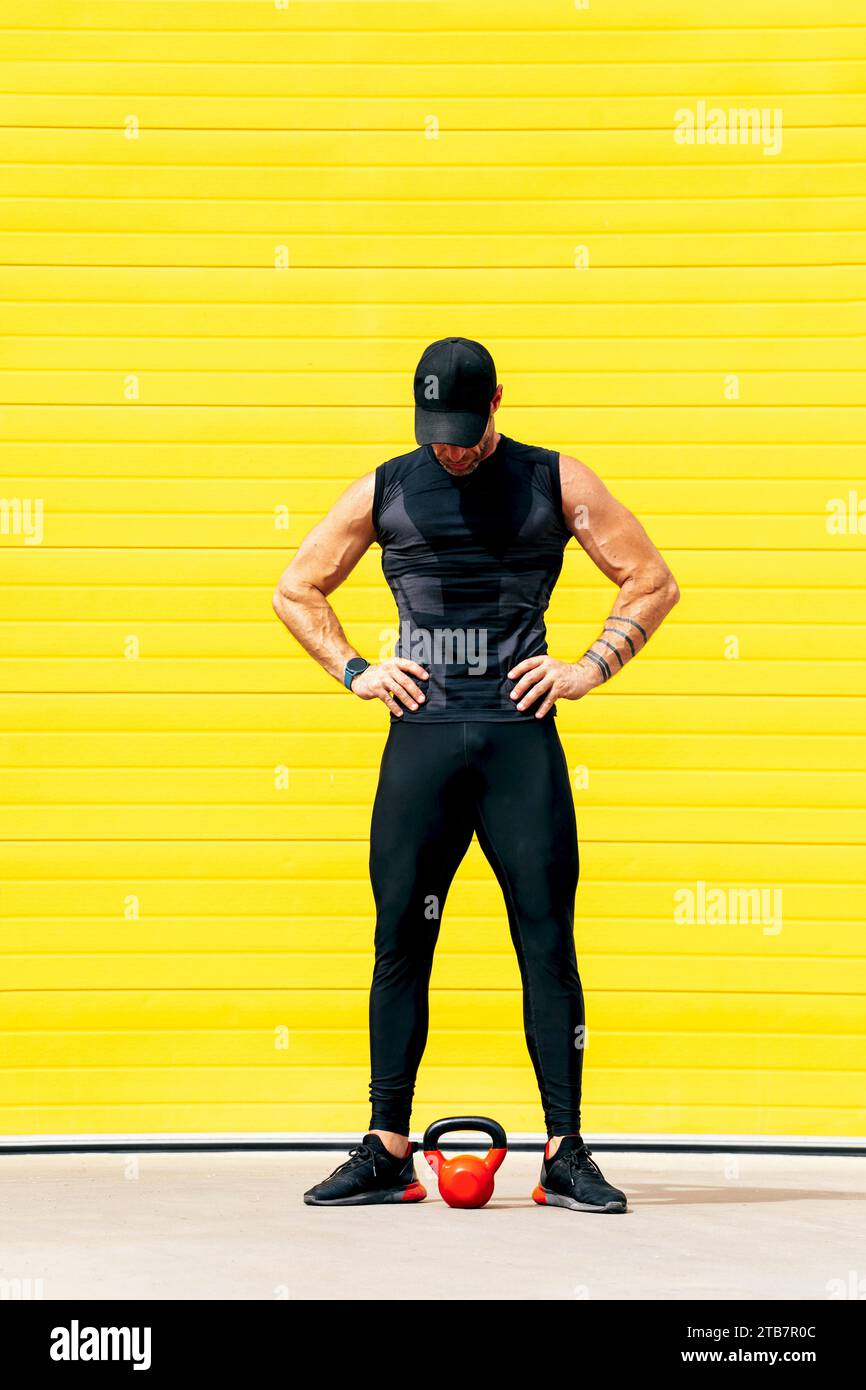 Anonymous muscular male athlete with arms akimbo standing with ...