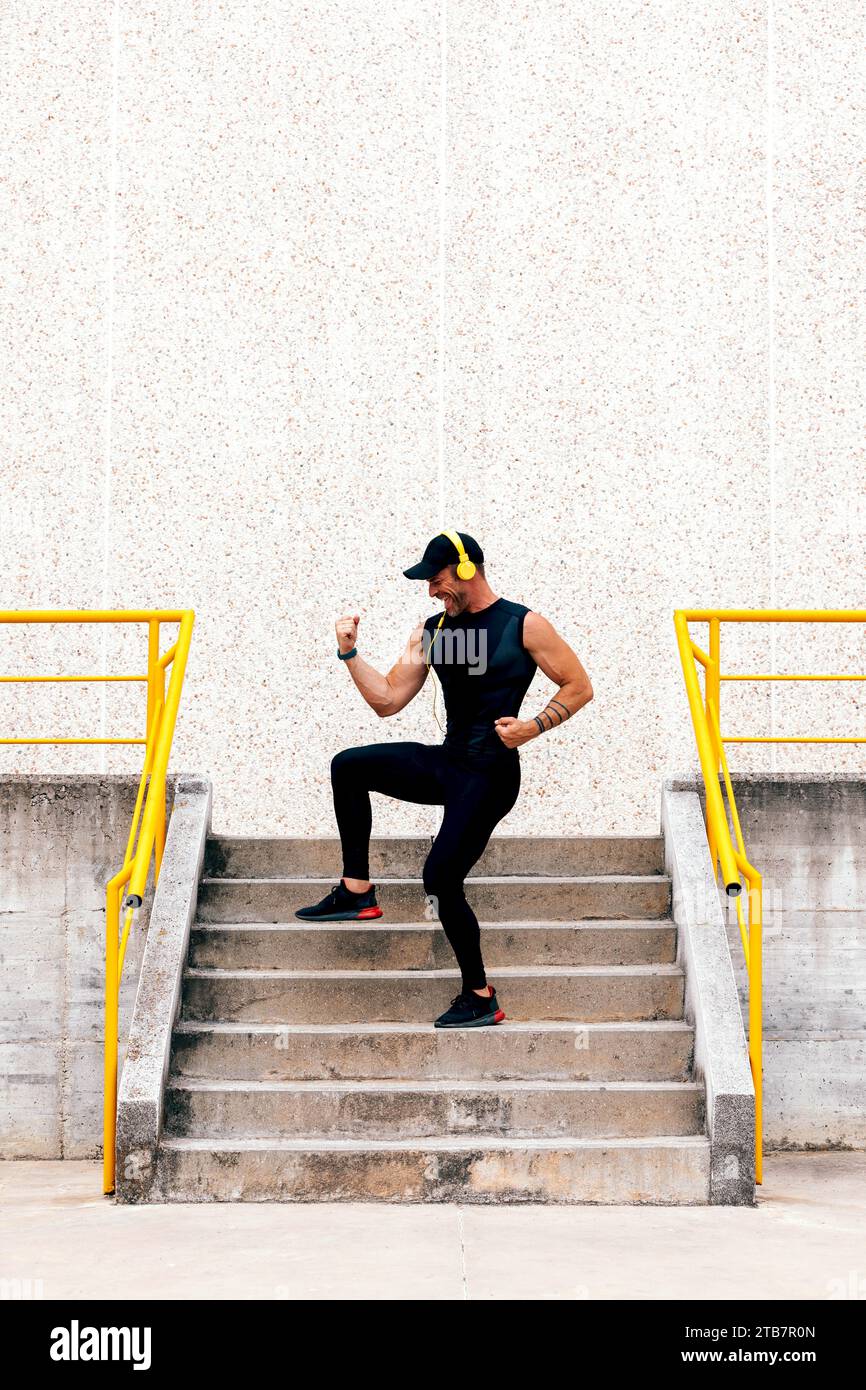 Full body side view of cheerful sportsman listening music over ...