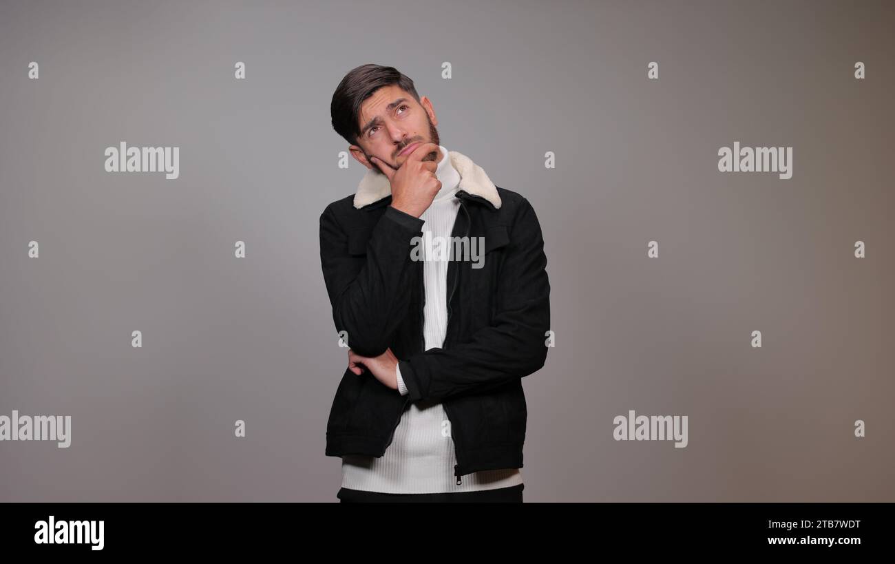A confused young man thinking against a gray background Stock Photo - Alamy