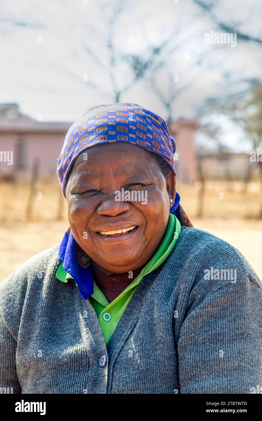 villager ,old african woman laughing at a good joke, house and dirt ...