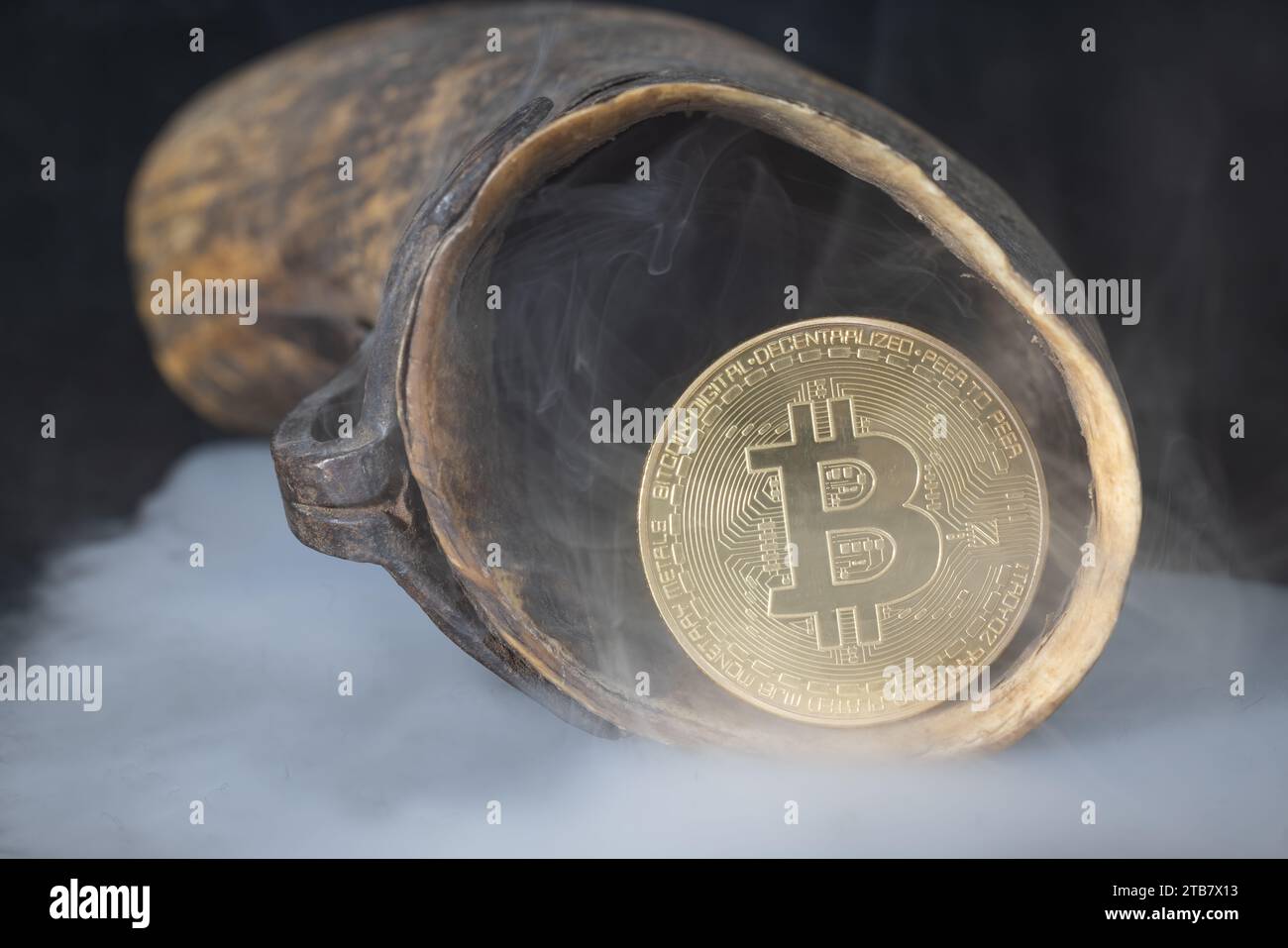 A digital currency coin is encased in a clear glass cup, with white ...