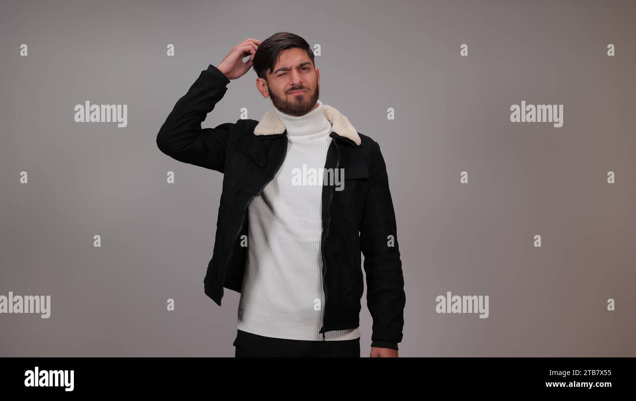 A confused young man thinking against a gray background Stock Photo - Alamy