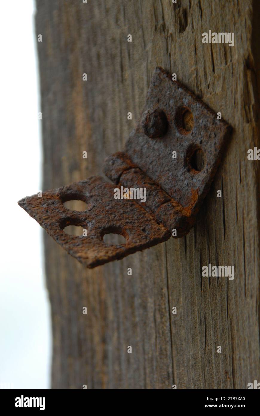wooden beam from which hangs an old, rusted hinge Stock Photo - Alamy