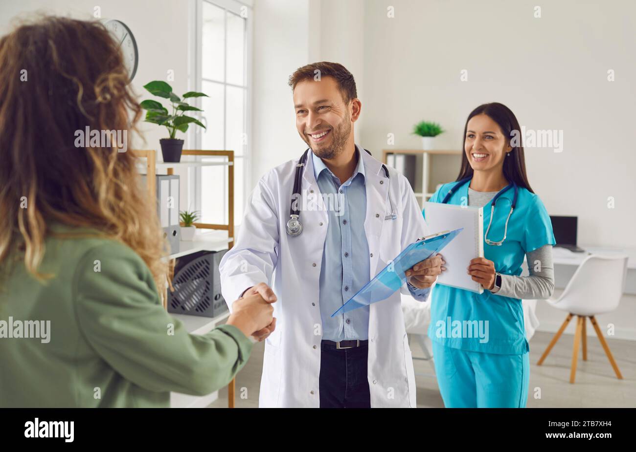 Doctor with Nurse Extend Handshake to Patient Stock Photo - Alamy
