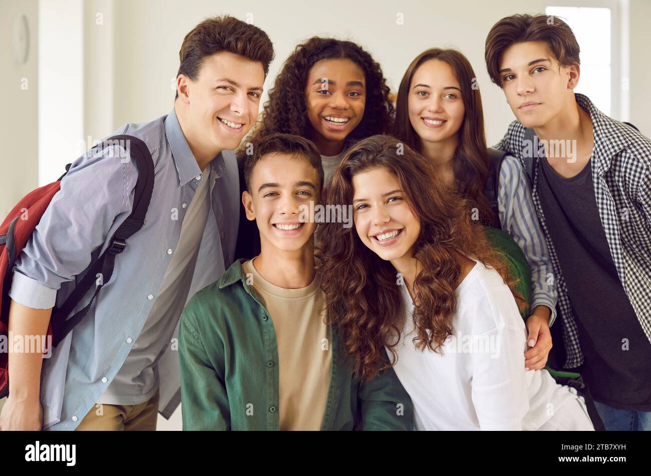 Group of a happy friends high school students standing together and looking cheerful at camera ...