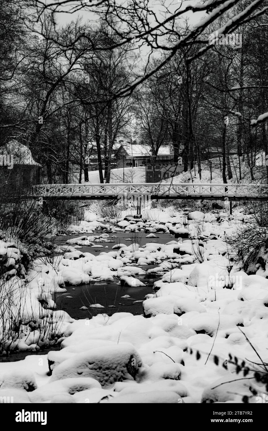 A peaceful winter scene featuring a stream winding its way through a ...