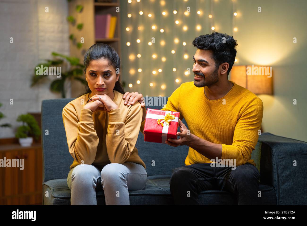 Angry indian girl rejecting gift from boyfriend while sitting on sofa ...