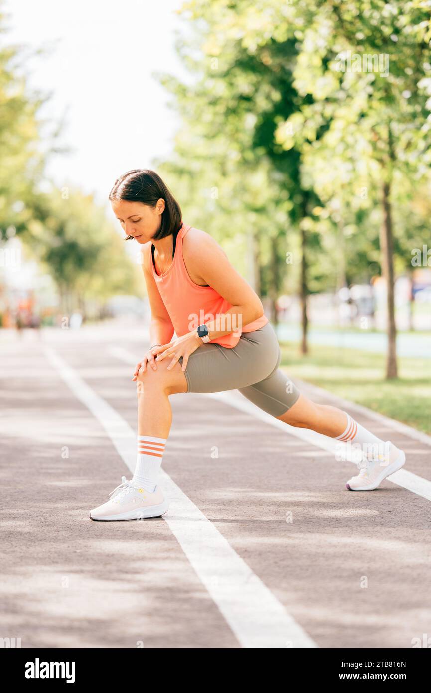 Vertical image of athlete woman stetching legs before marathon Stock ...