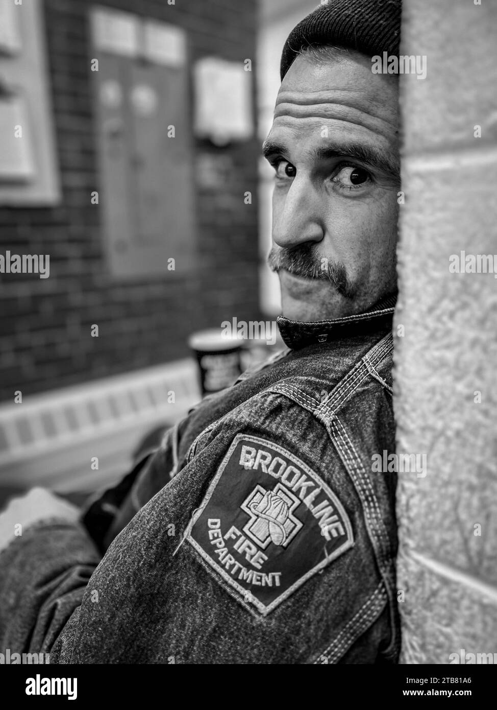 A vertical grayscale shot of a male in a Brookline Fire Department ...