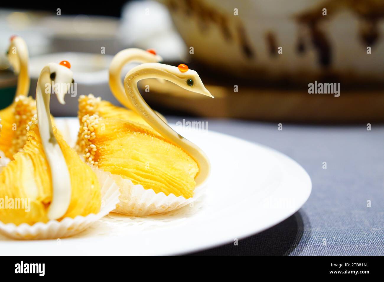 A white table with an ornate swan-shaped durian pastry resting atop it ...