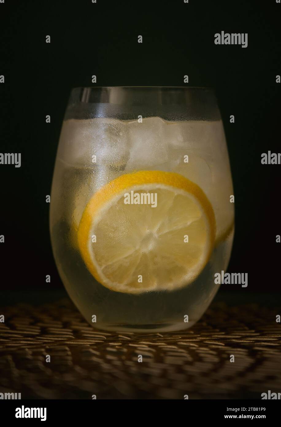 Gin and Tonic highball cocktail with ice and lemon in front of green background Stock Photo - Alamy