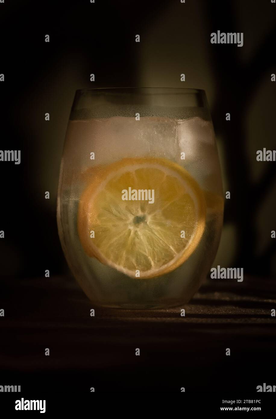 Gin and Tonic highball cocktail with ice and lemon in front of green background Stock Photo - Alamy