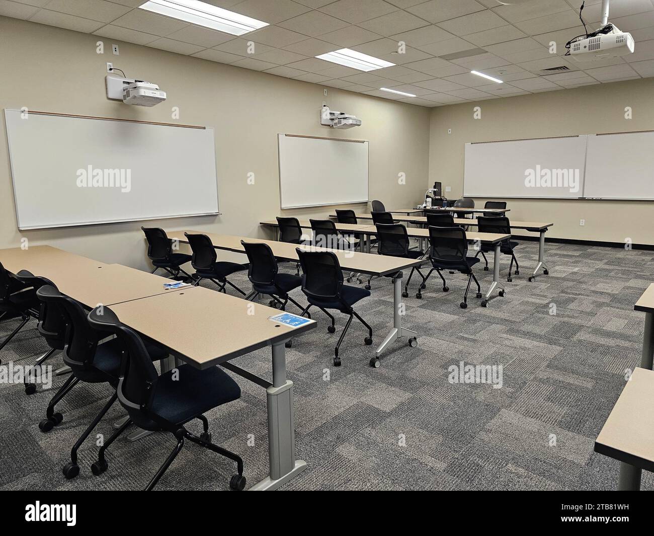 An empty classroom interior, with rows of desks and a projector ...