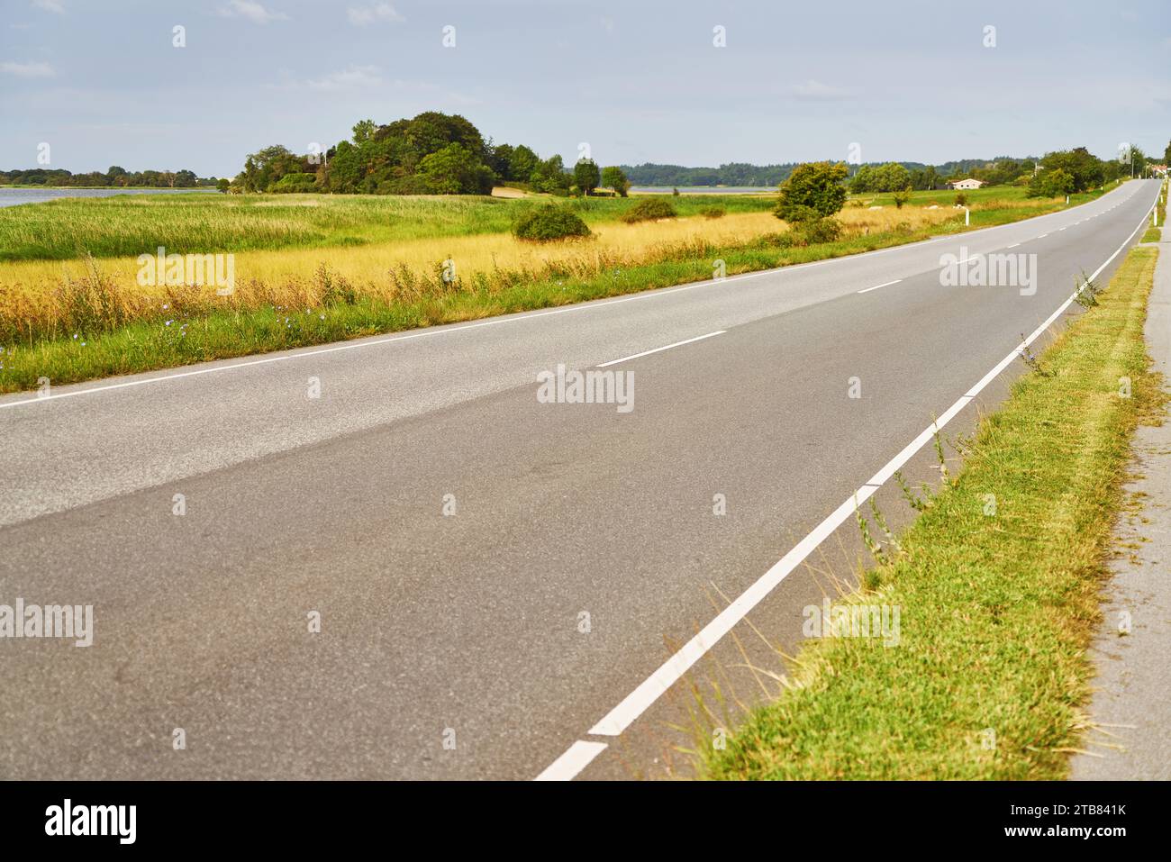 Road with two lanes as straight line through farmland in Sweden Stock ...
