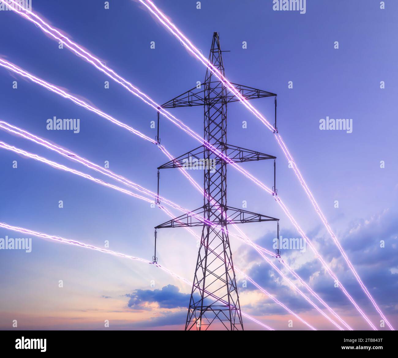 Electric transmission tower with glowing wires against the sunset sky ...