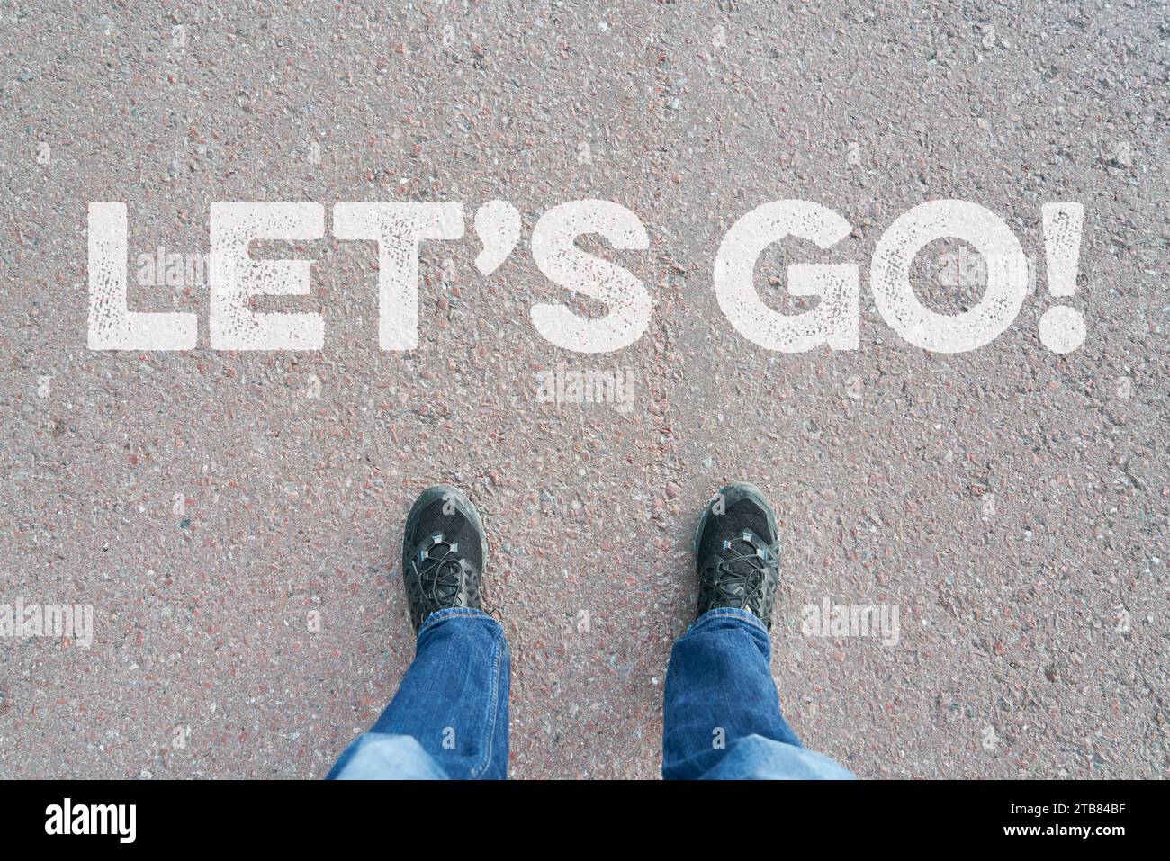 Let's go written as motivational quote on asphalt on road with shoes ...