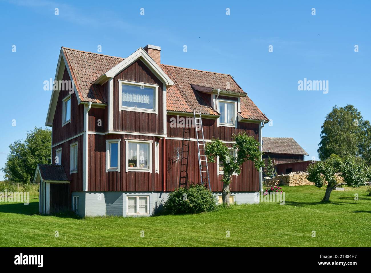 Red Swedish two-story house with ladder leaning on wall to reach the ...