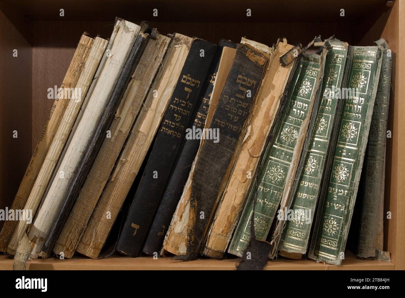 Dusty, worn and faded leather-bound Jewish holy books stacked upright ...