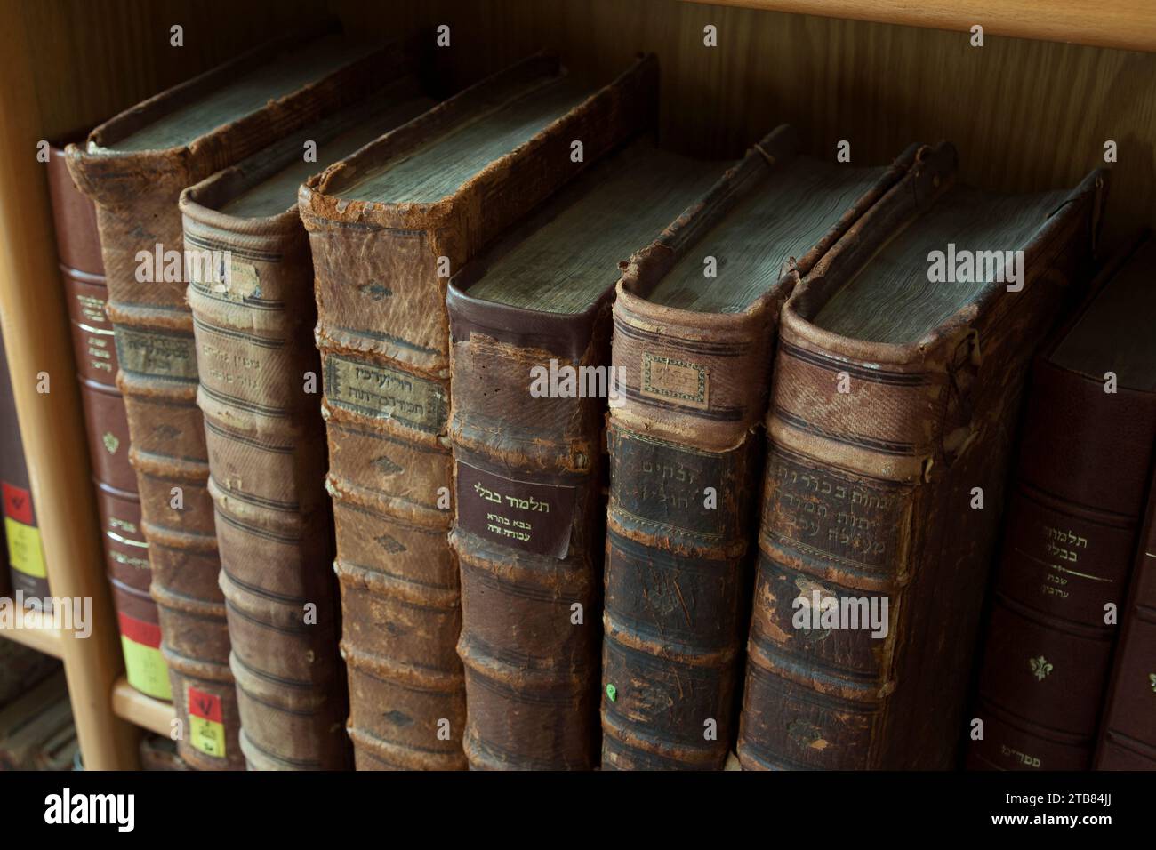 Dusty, worn and faded leather-bound Jewish holy books stacked upright ...