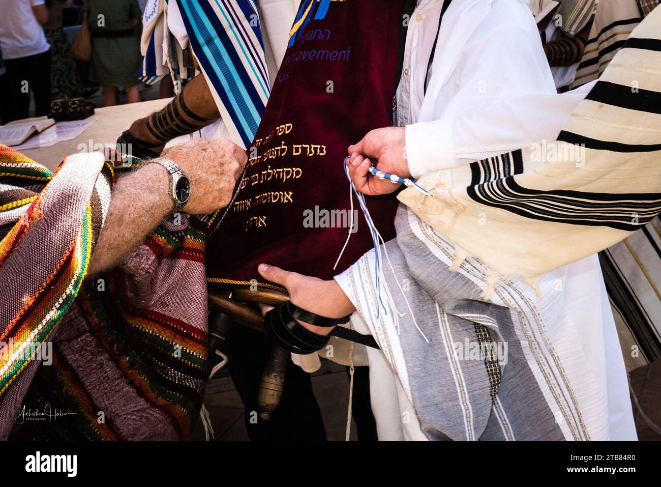 Hands extend to touch the Torah scroll as it is carried around a ...
