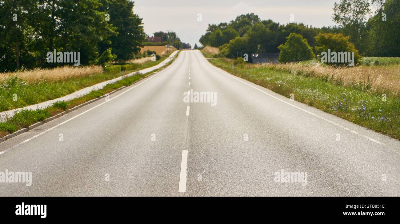 Straight asphalt road going up hill into village in Sweden Stock Photo ...