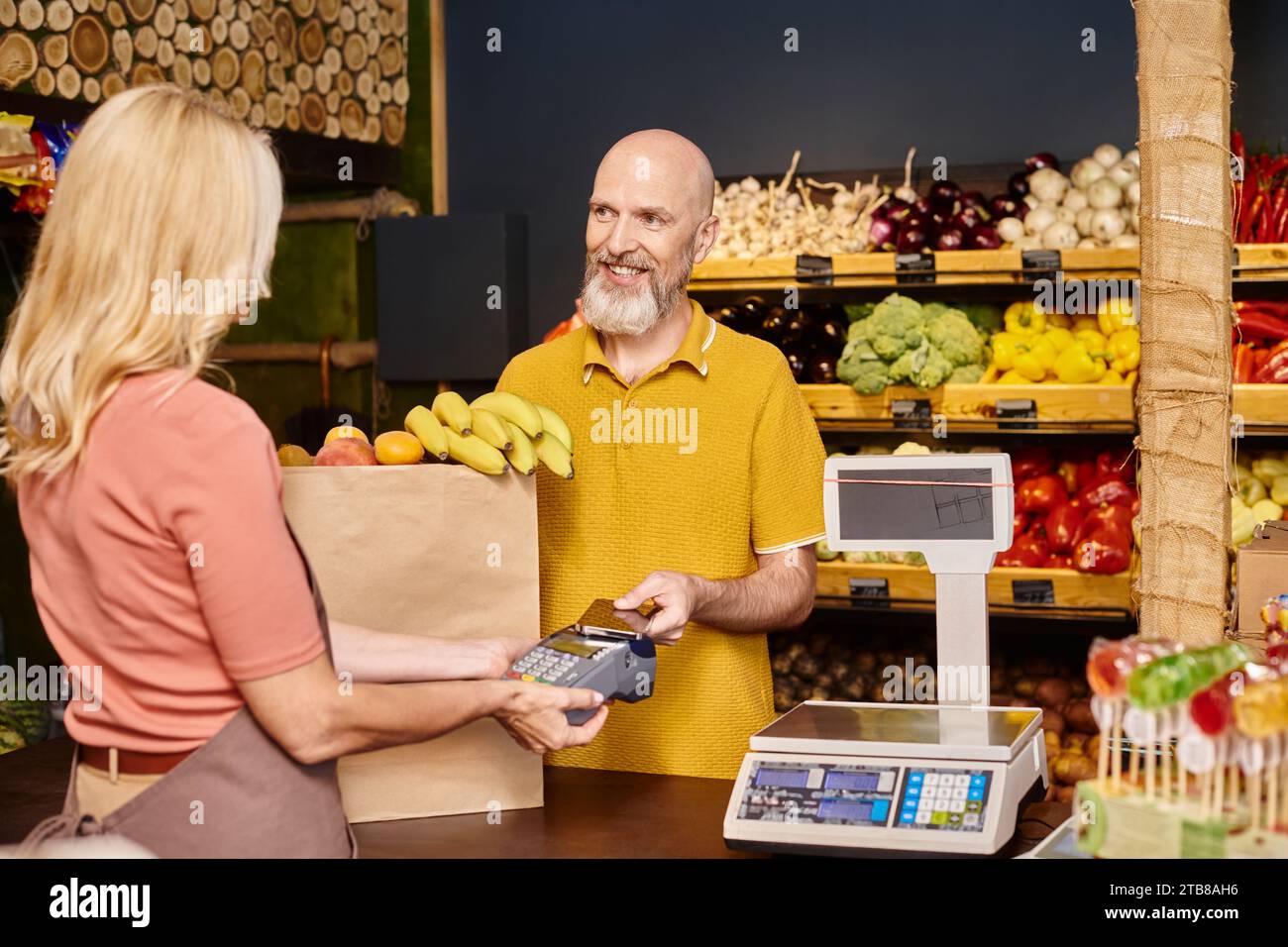 focus on cheerful customer paying with his phone for fresh fruits and ...