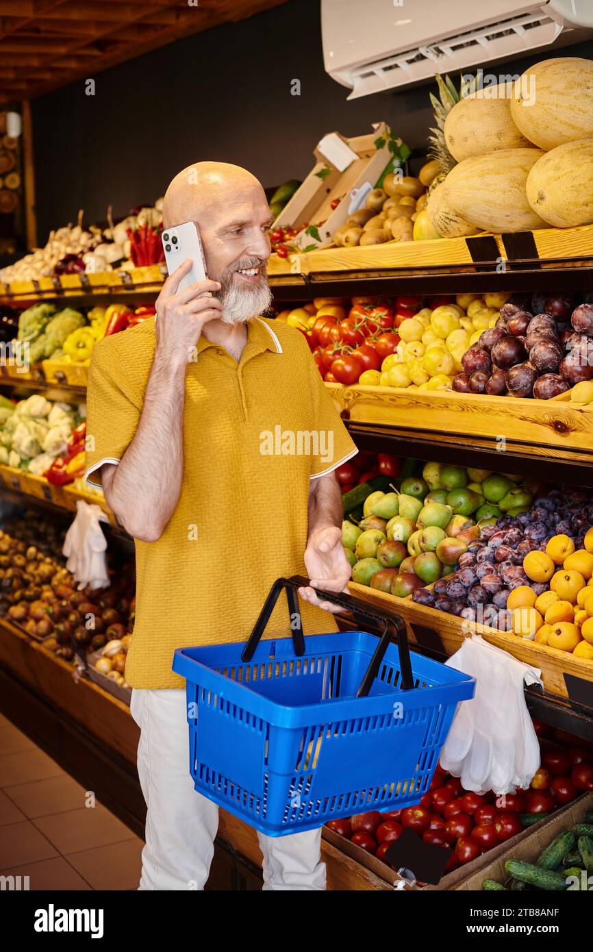 good looking mature male customer with shopping basket talking by phone ...