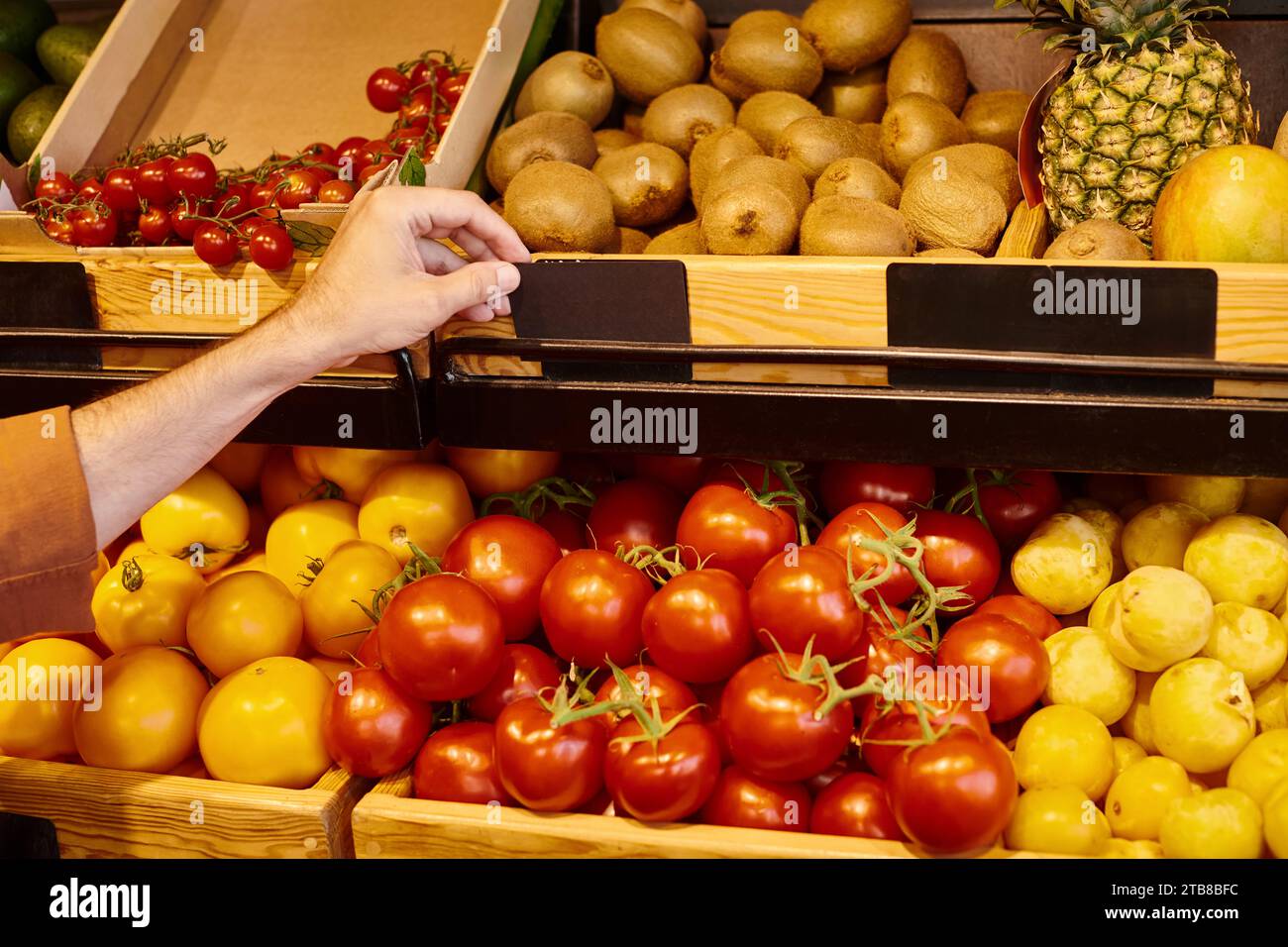 cropped view of mature male seller putting price tag on grocery stall ...