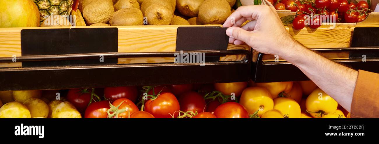cropped view of mature male seller putting price tag on stall with ...