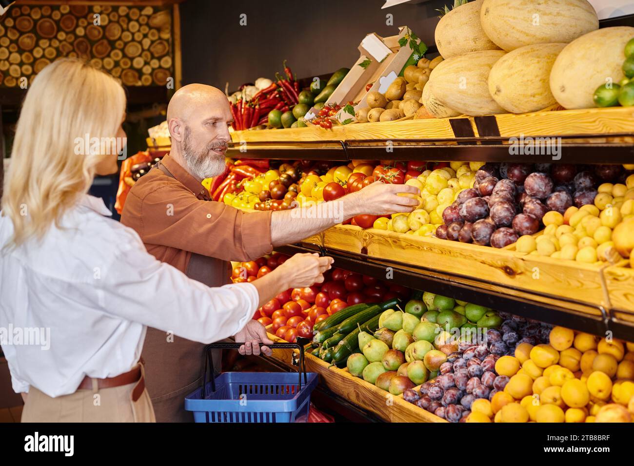focus on bearded mature seller helping his blurred senior female ...