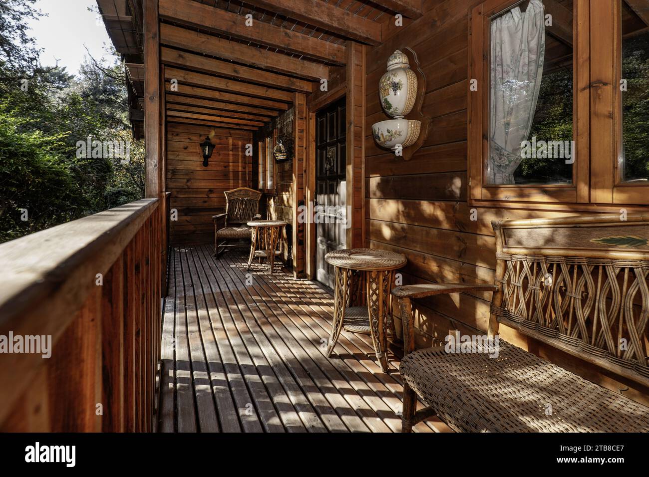 Front porch of a wooden cabin with wooden and wicker furniture Stock ...
