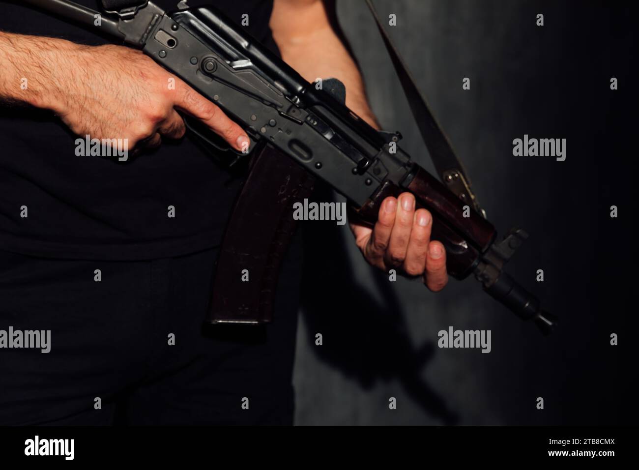 Men's hands with a machine gun on a black background Stock Photo - Alamy
